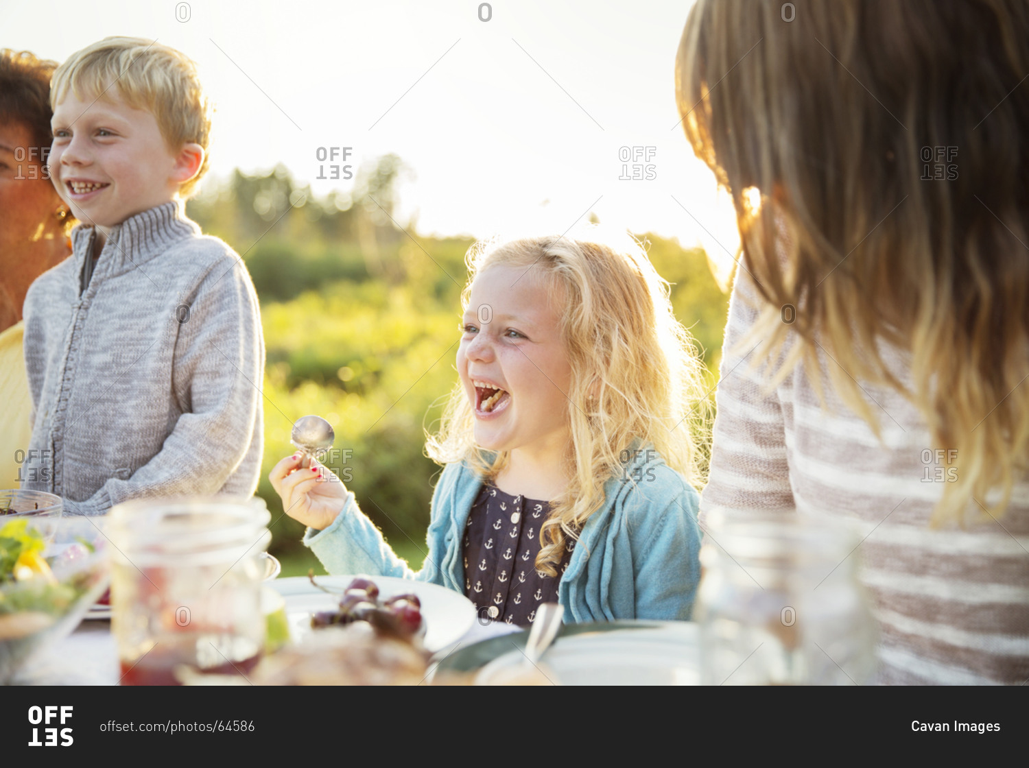 Portrait of young children sitting at an outdoor table stock photo - OFFSET