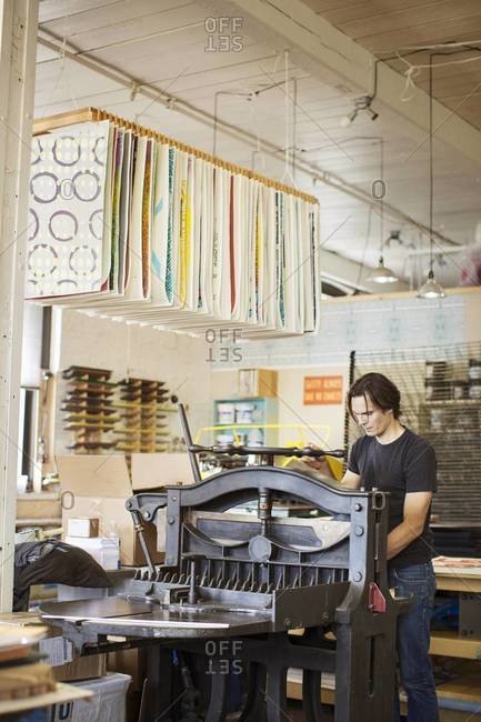 Young pressman is studio working printing press machine - Stock Image ...