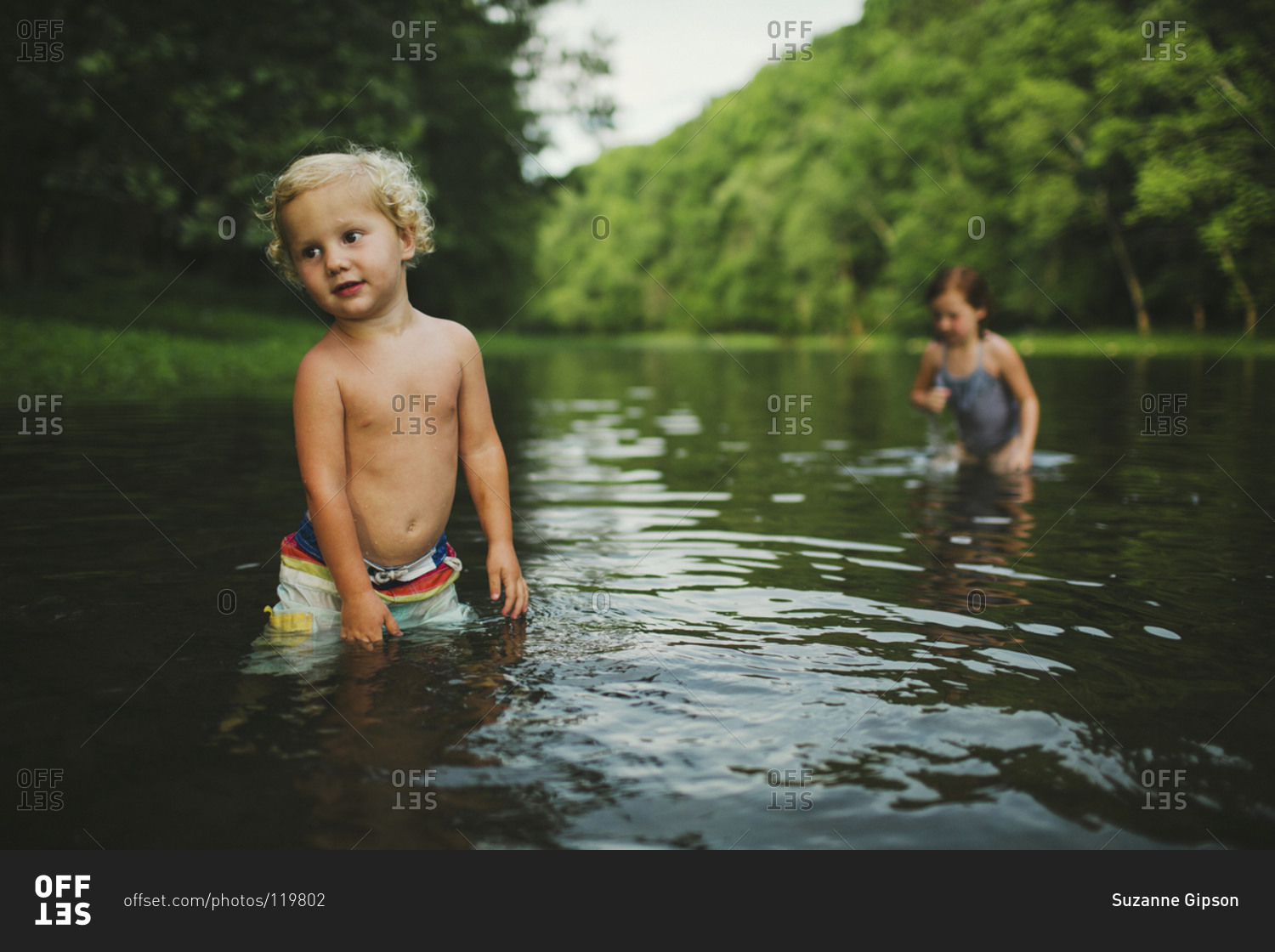 Children playing in a river stock photo - OFFSET
