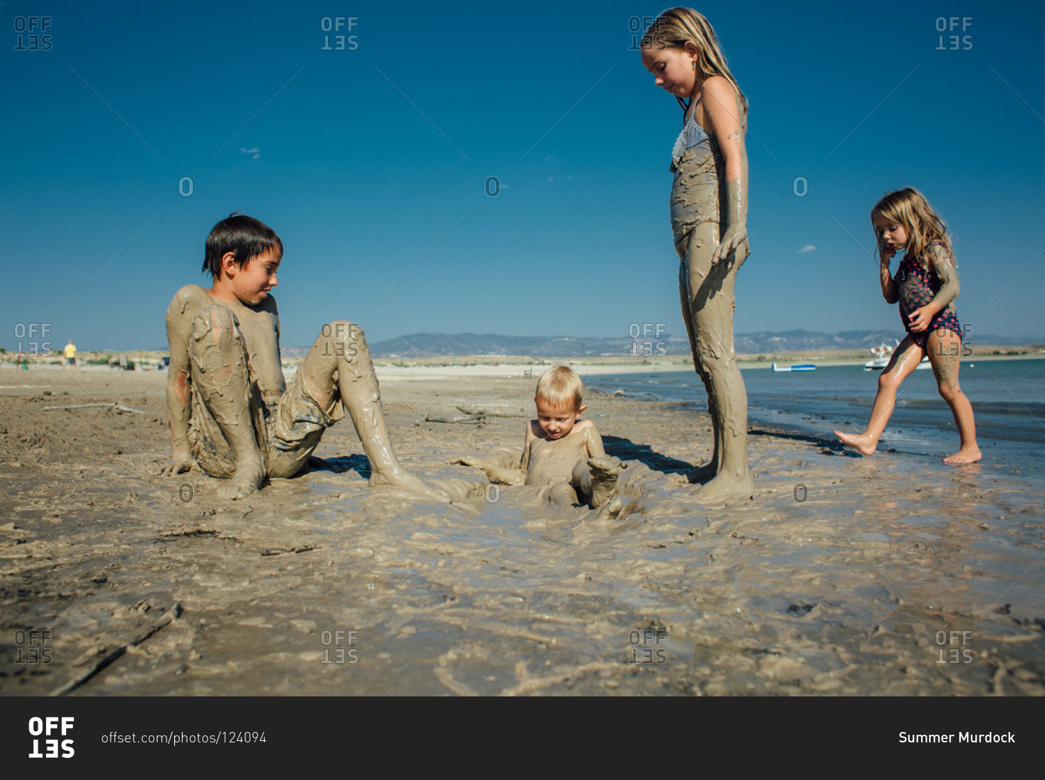 Children covered in mud on the beach stock photo - OFFSET