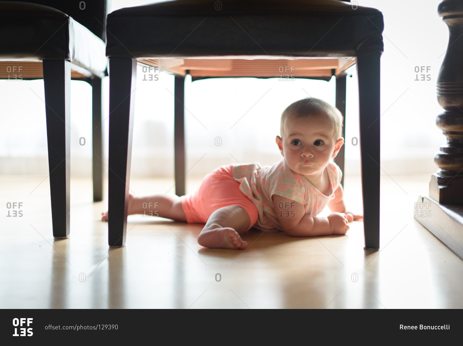 Baby crawling under a chair stock photo - OFFSET