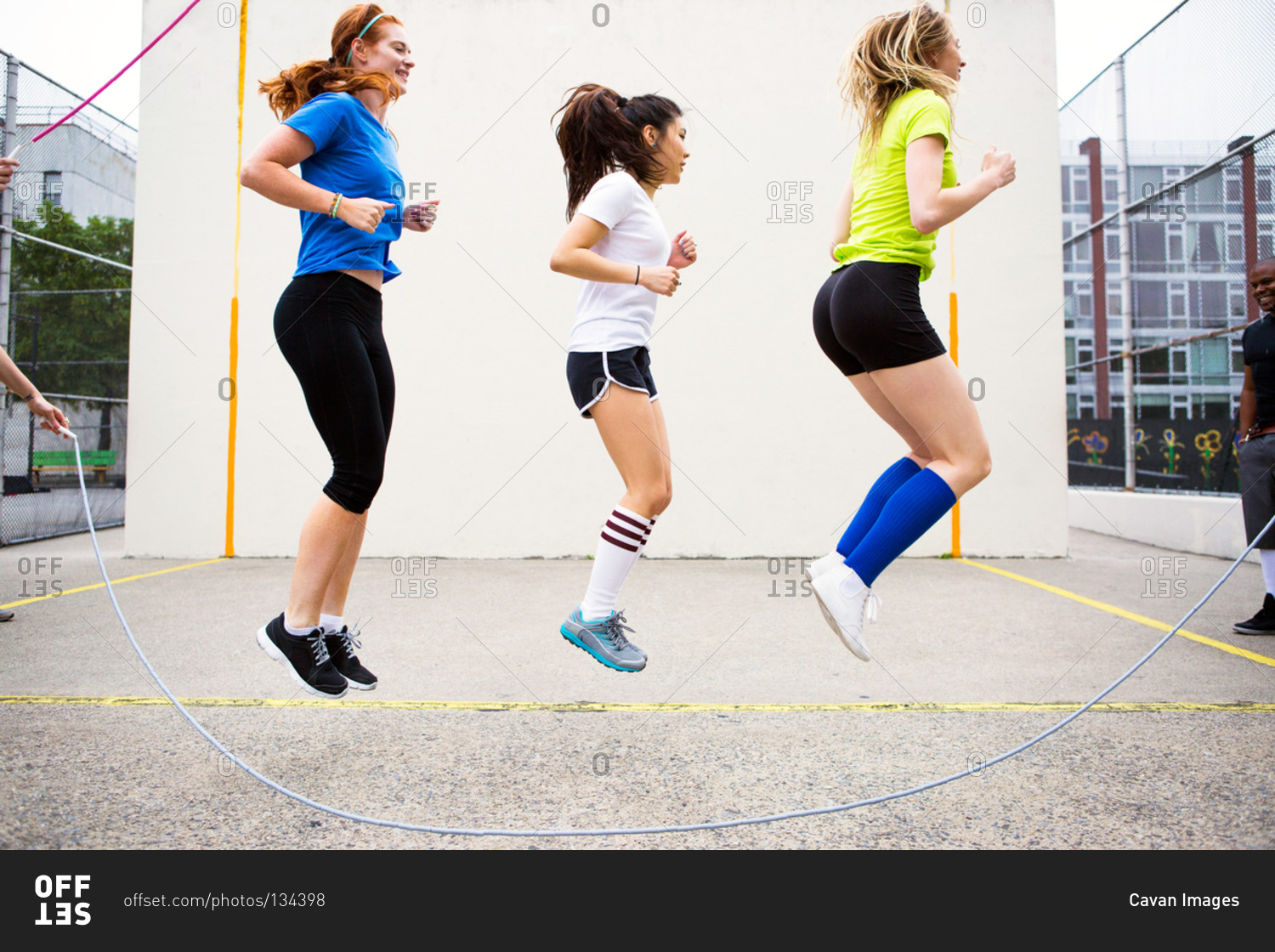 Young adults skipping rope in the park stock photo - OFFSET