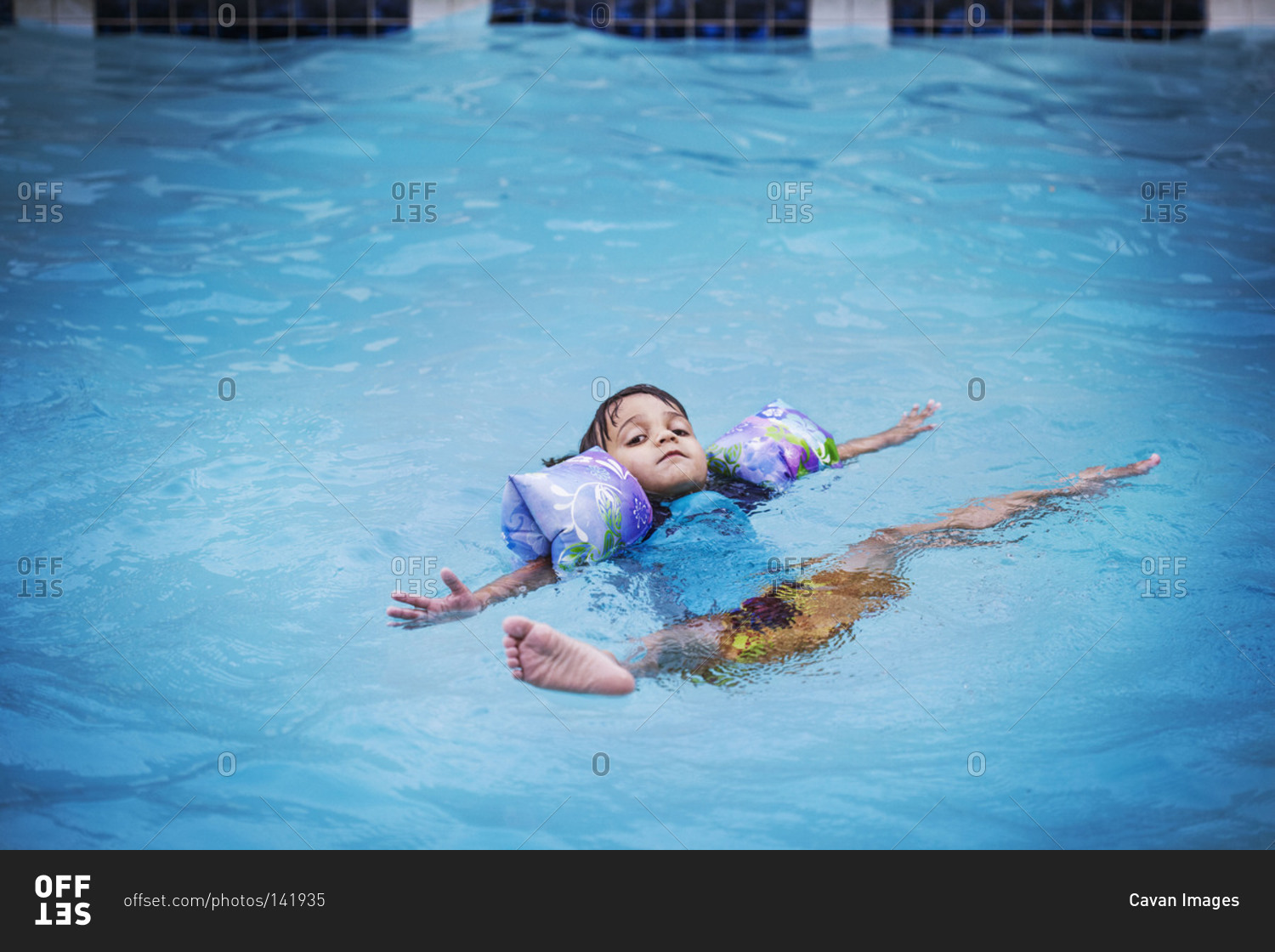 Kid floating in a pool stock photo - OFFSET