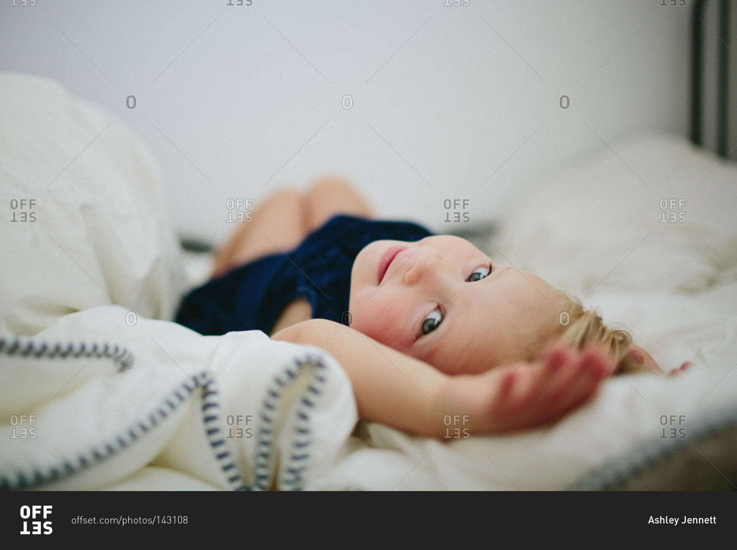 Little girl lying in bed stock photo - OFFSET