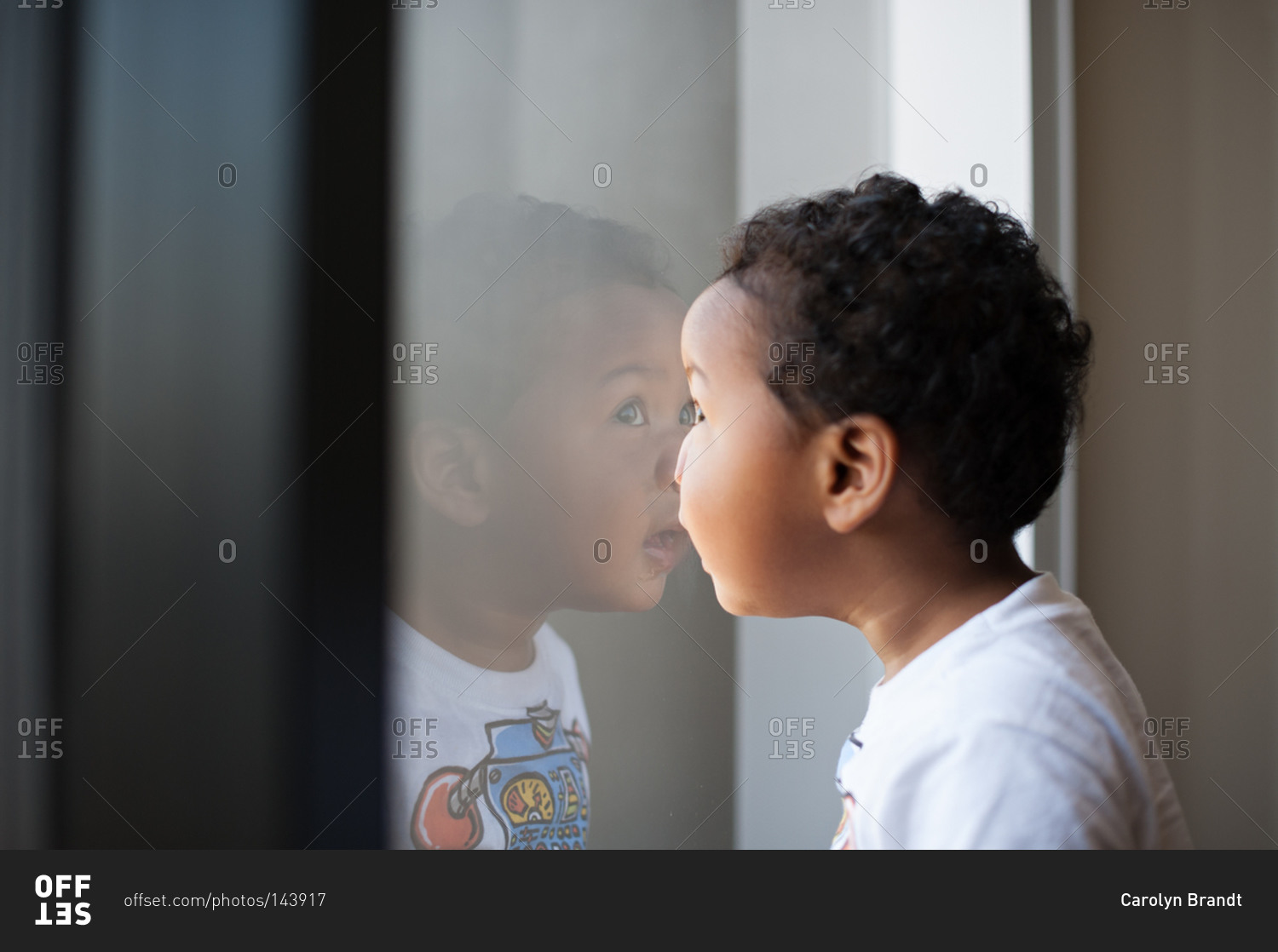 A boy presses his face against glass window stock photo - OFFSET