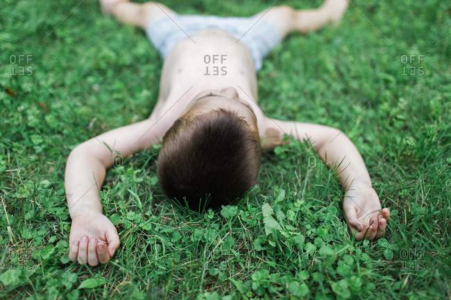 Boy sprawled out on the grass stock photo - OFFSET