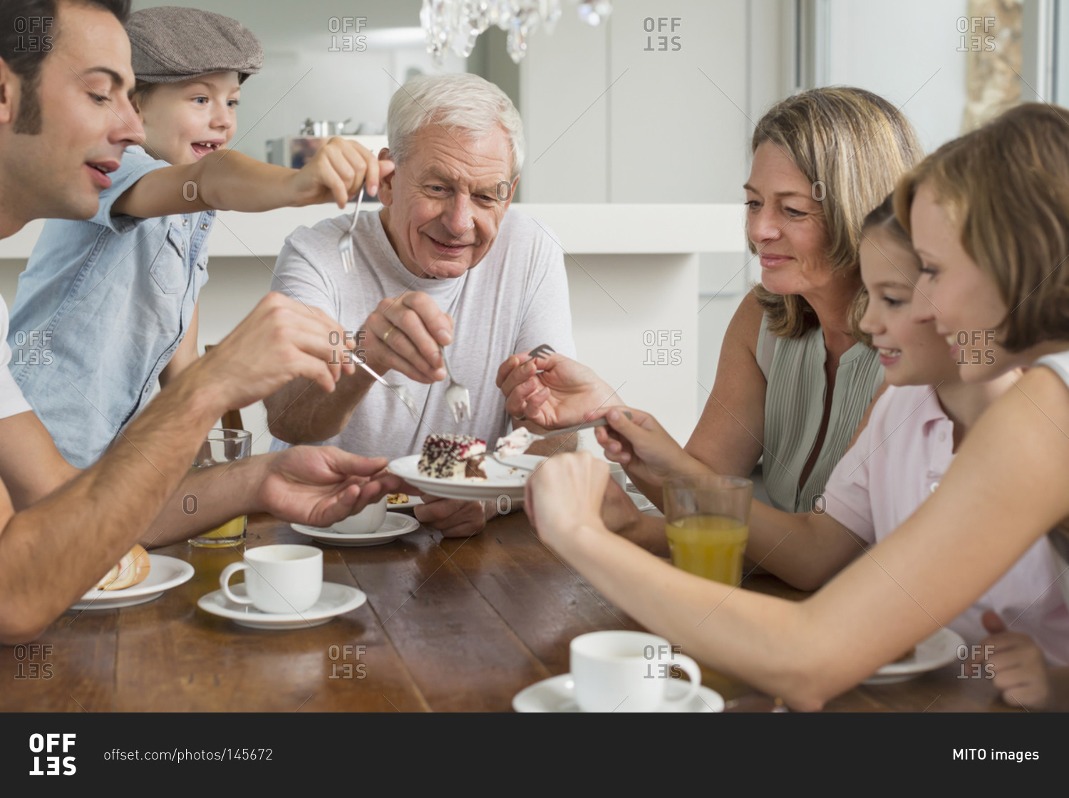 Extended family at table eating cake - Stock Image - Everypixel