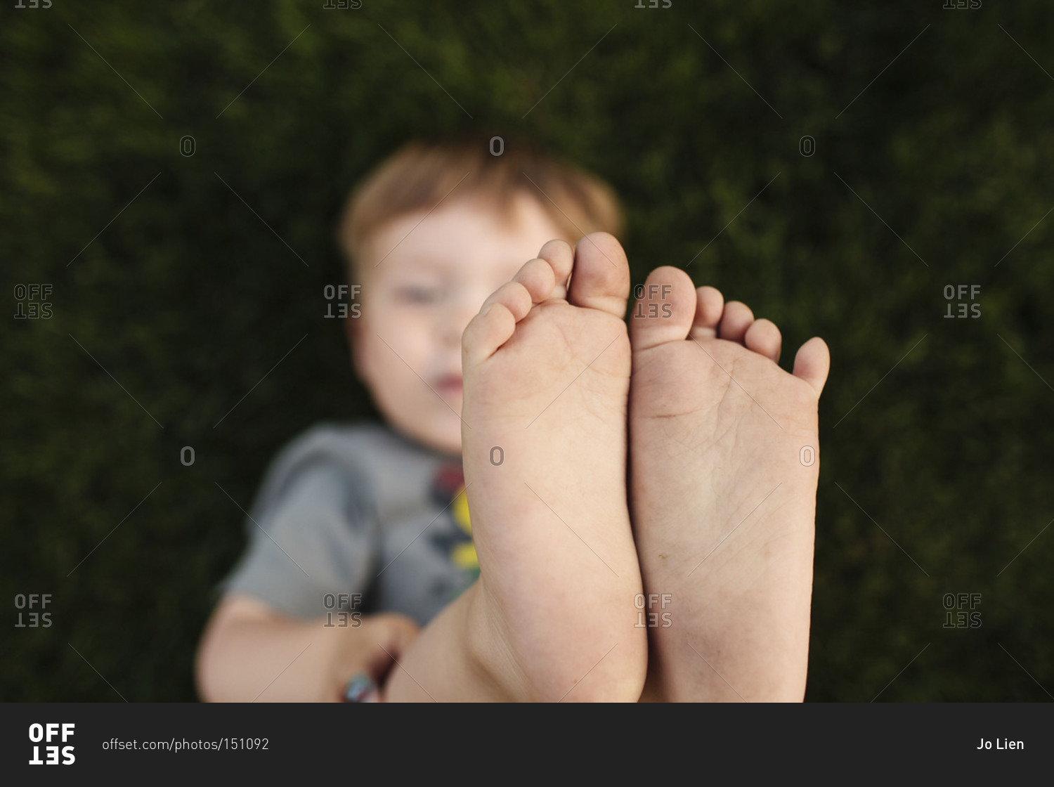 Little boy lying down sticking feet in the air stock photo - OFFSET