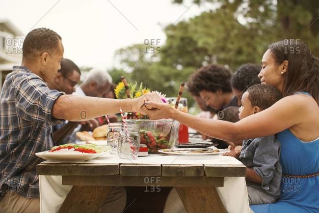 Family praying before picnic - Stock Image - Everypixel