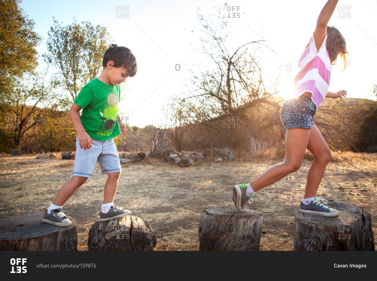 Kids jumping across logs - Offset stock photo - OFFSET