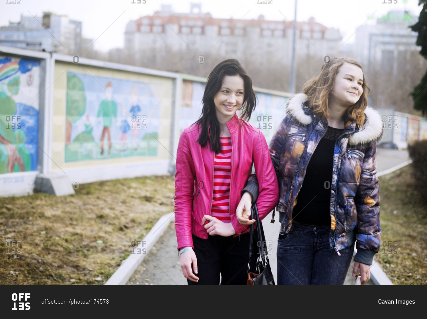 Two girls walking with arms linked stock photo - OFFSET