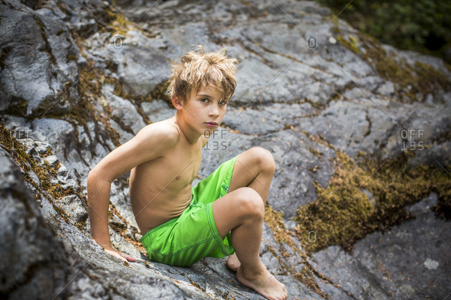 Boy sitting on rock - Offset stock photo - OFFSET