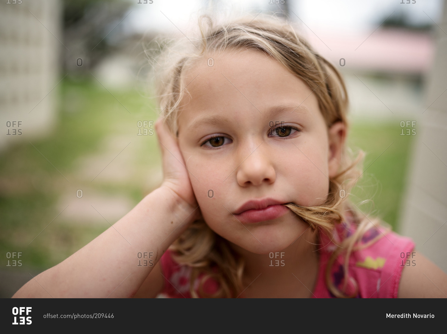 Portrait of wavy hair girl chewing on hair stock photo - OFFSET