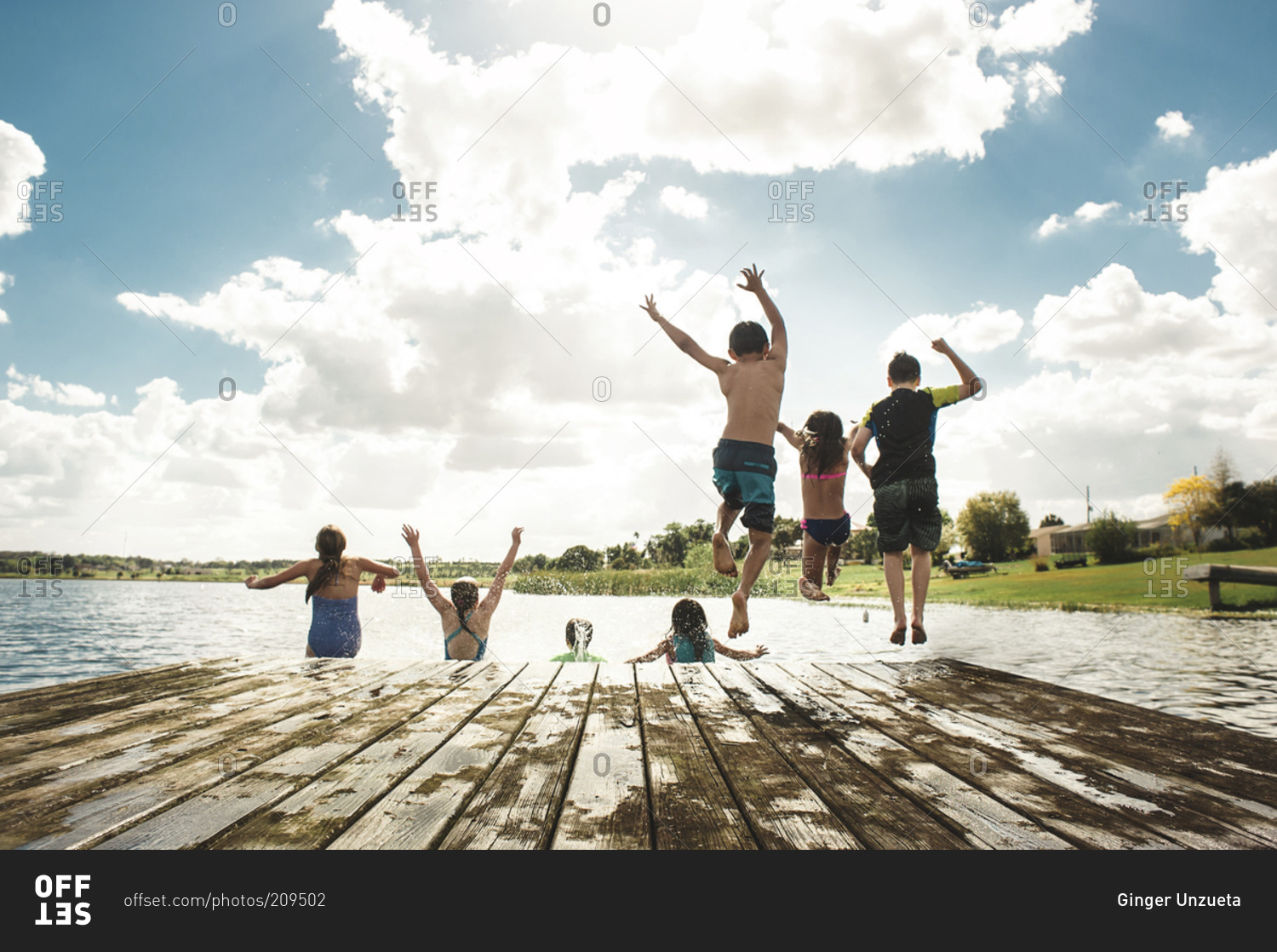 Children running off a dock into lake stock photo - OFFSET