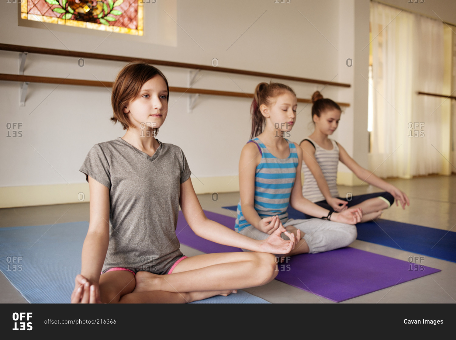 Three young teens in seated yoga position stock photo - OFFSET