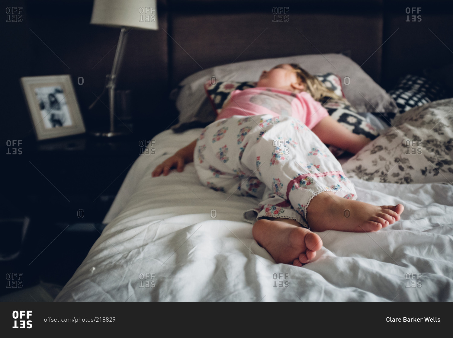 Girl sprawled out asleep on bed stock photo - OFFSET