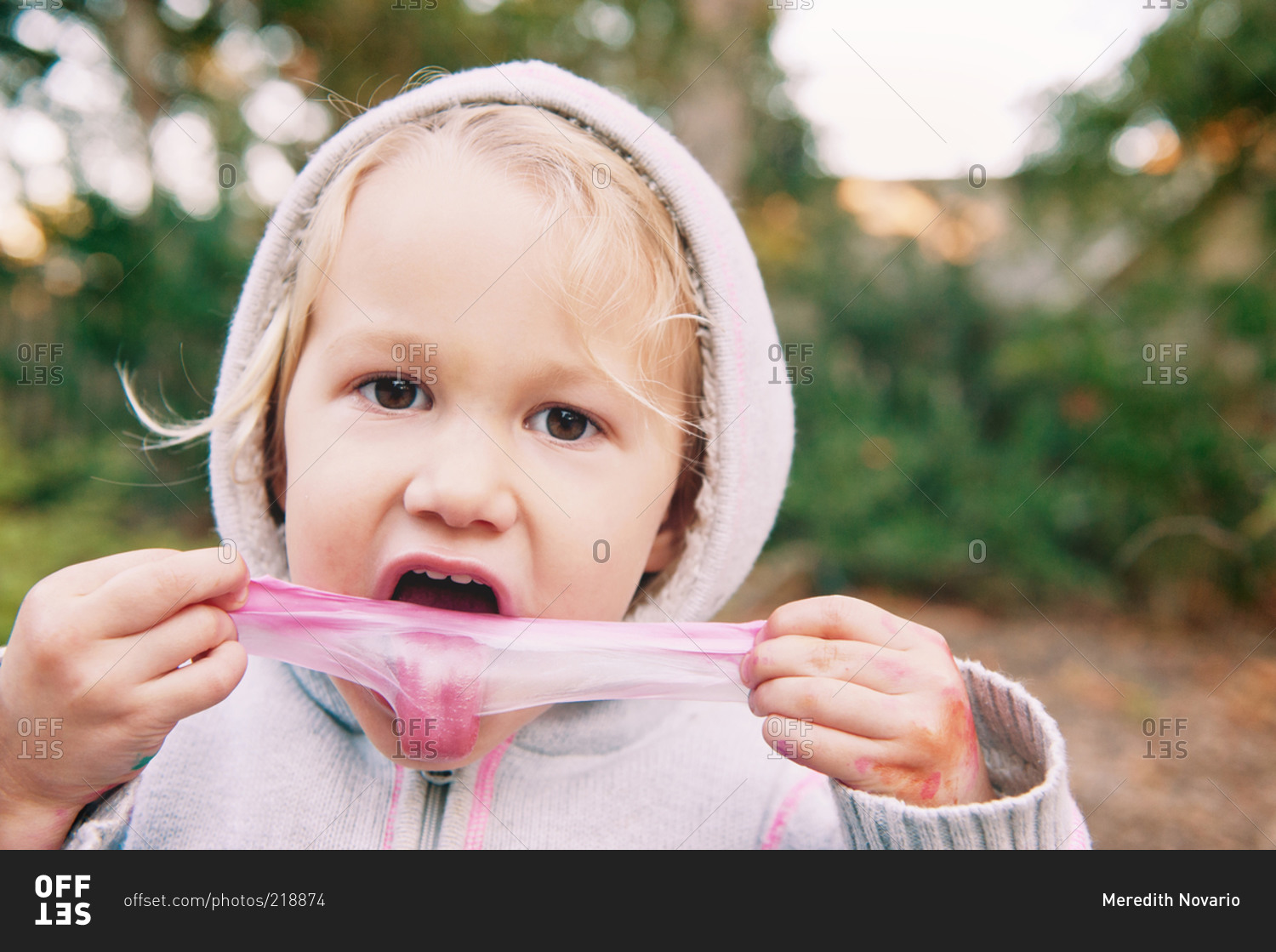 Young girl stretching chewing gum out of her mouth stock photo - OFFSET