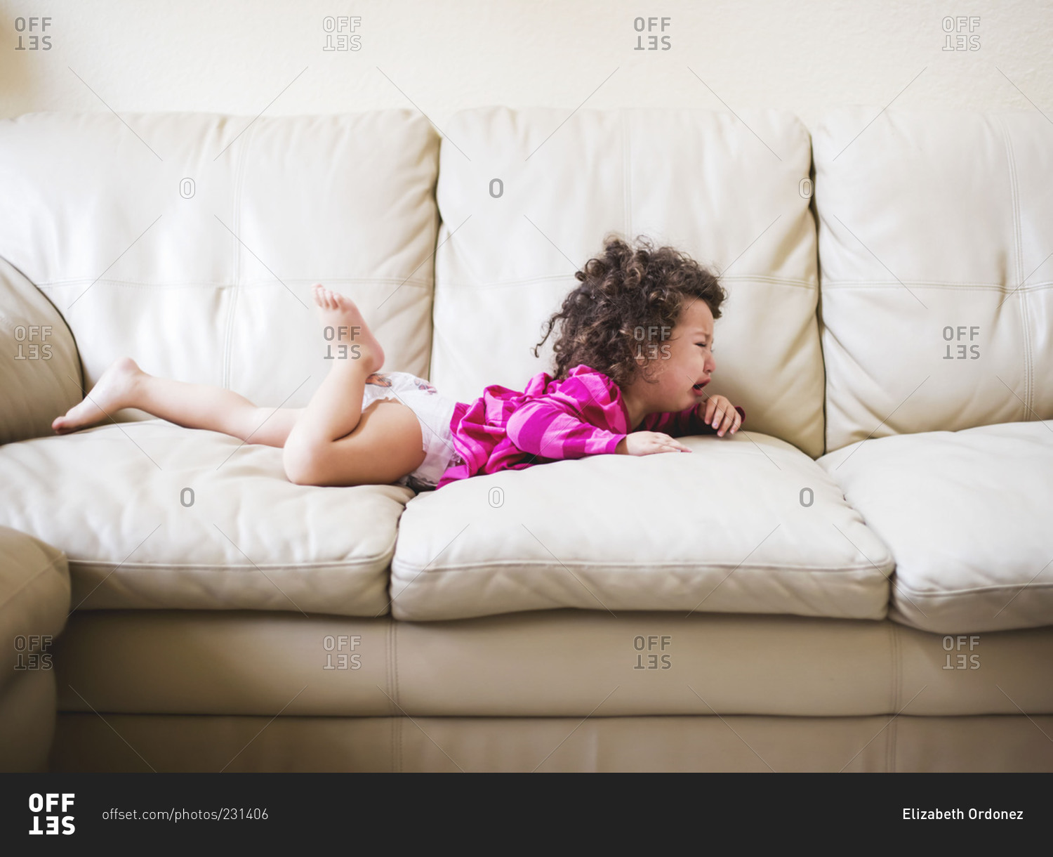 Little girl having a temper tantrum on the sofa stock photo - OFFSET