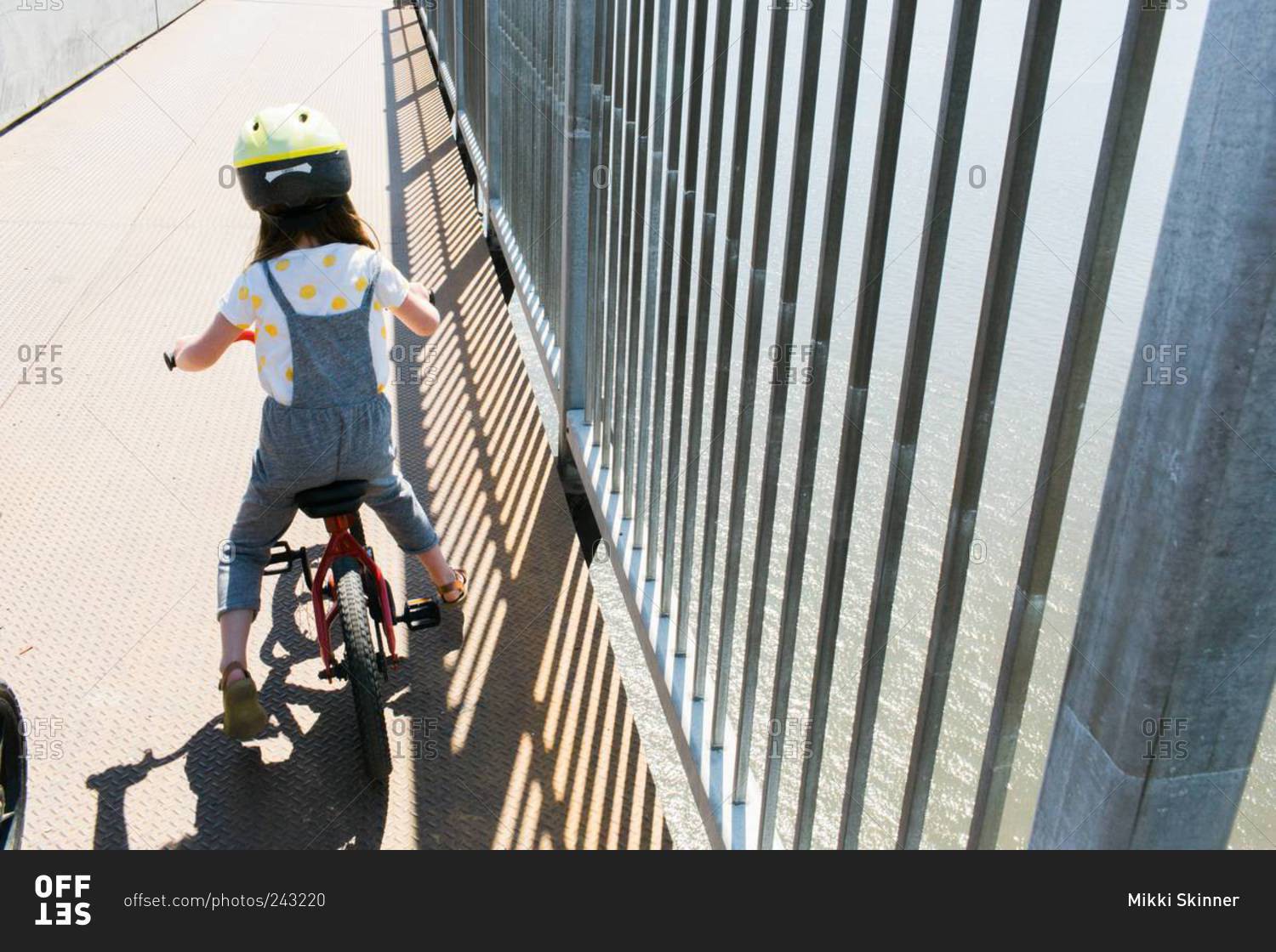 Girl pushing off on bike on bridge stock photo - OFFSET