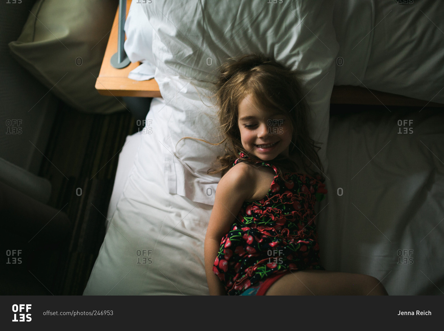 Little girl lying on hotel bed smiling stock photo - OFFSET