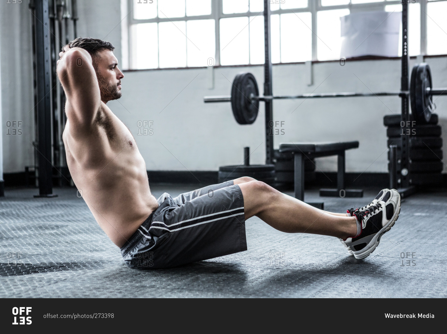 Fit shirtless man doing sit ups at the gym stock photo - OFFSET