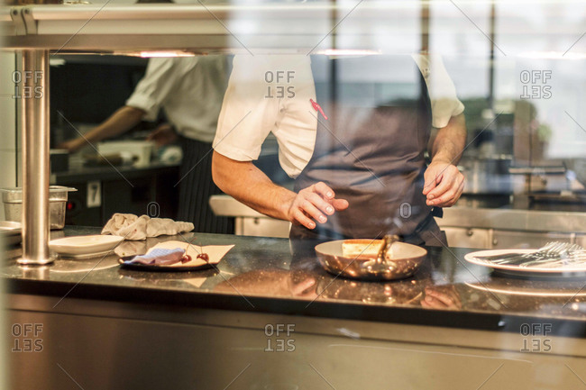 Chef preparing food behind a window in a restaurant kitchen stock photo ...