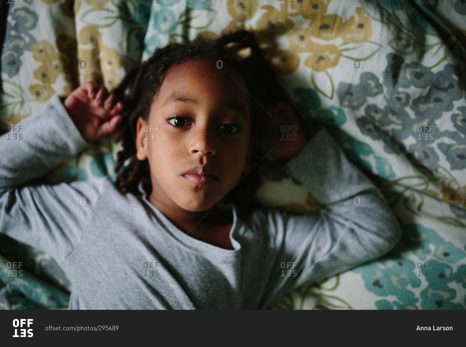 Portrait of a little girl lying on a floral blanket stock photo - OFFSET