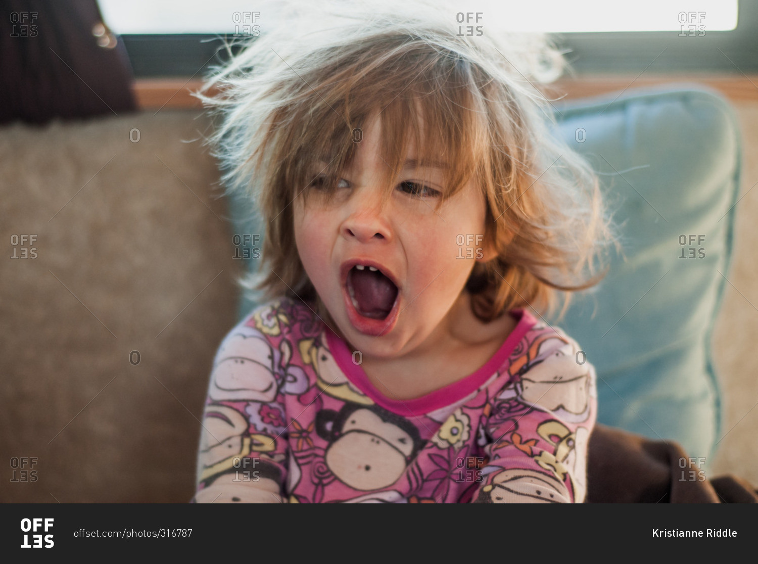 Little girl with bedhead yawning stock photo - OFFSET