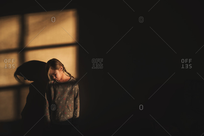 Sad girl in a dark room stock photo - OFFSET