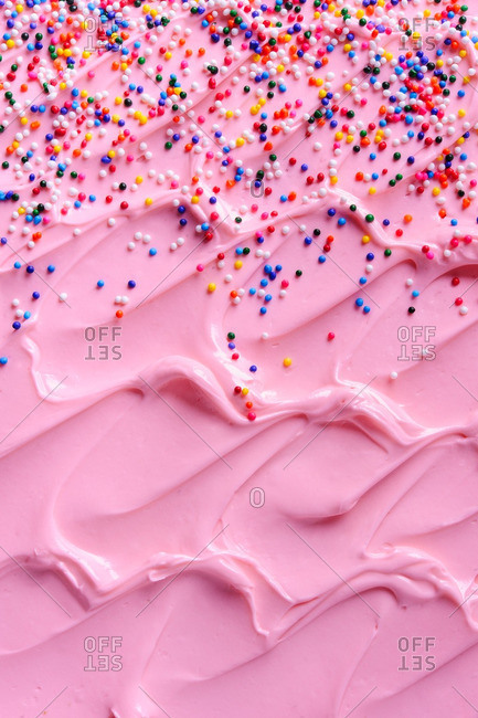 Close-up of a birthday cake frosted with pink icing and nonpareils ...