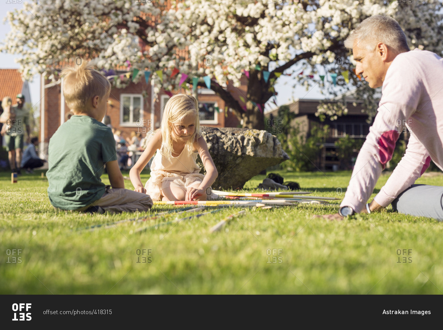 Children playing game in yard with their grandfather stock photo - OFFSET