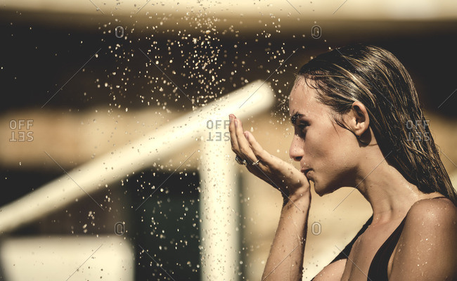 Woman In A Bathing Suit Rinsing Off In An Outdoor Shower After Swimming