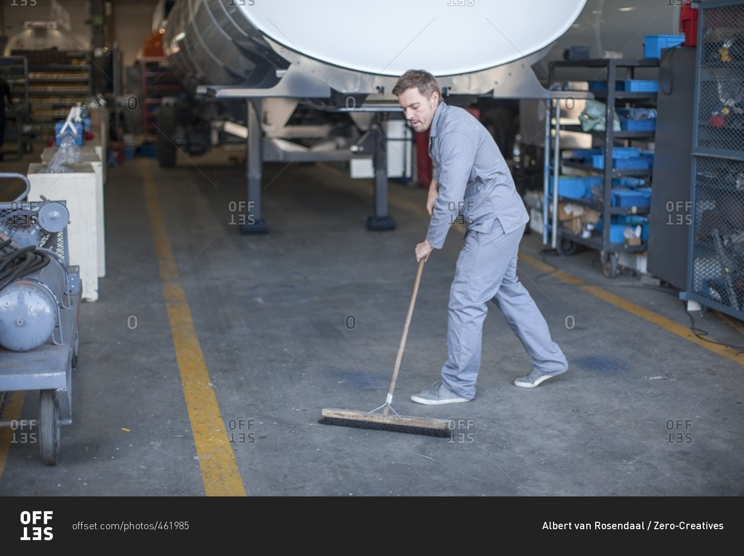 Factory worker sweeping factory floor stock photo - OFFSET