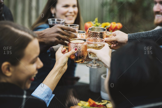 High angle view of happy friends toasting drinks while sitting in ...
