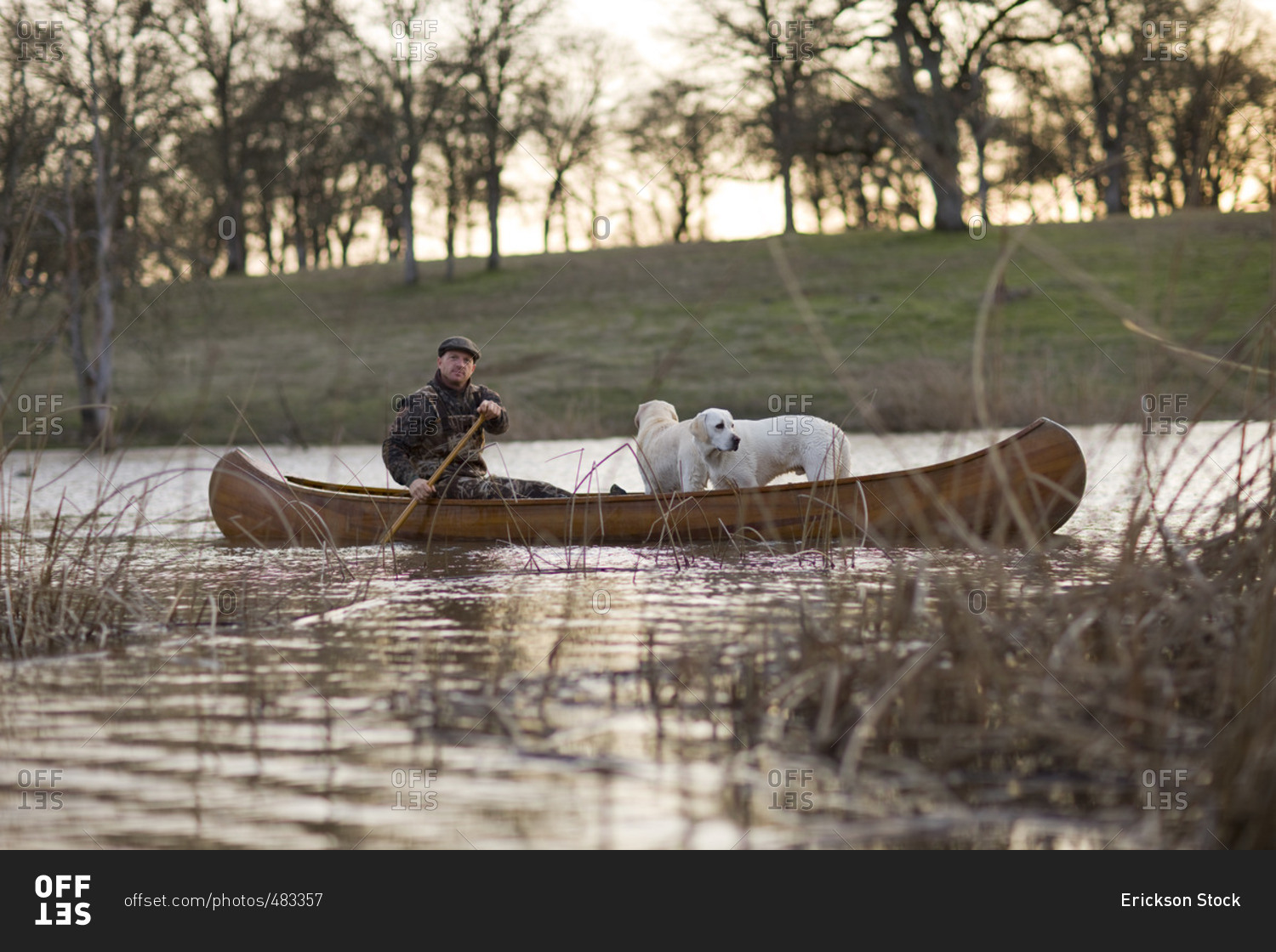 Hunter in a canoe with his two dogs - Stock Image - Everypixel