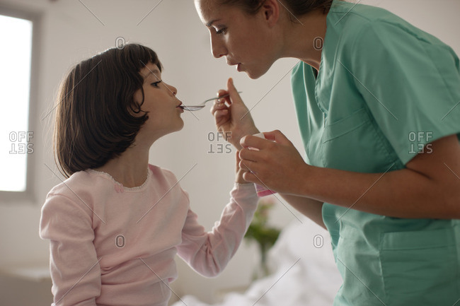 Nurse giving a young patient a dose of medicine. stock photo - OFFSET