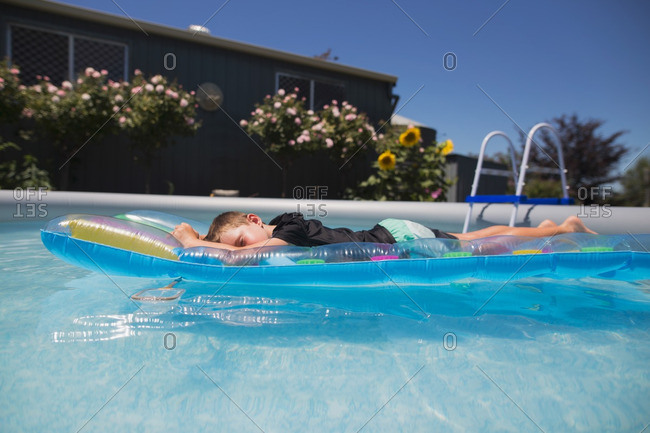 Boy lying on a pool float stock photo - OFFSET