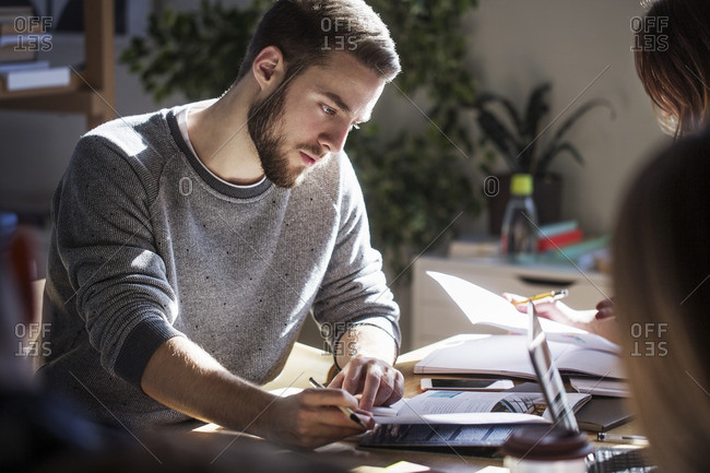 Man studying at table in classroom stock photo - OFFSET