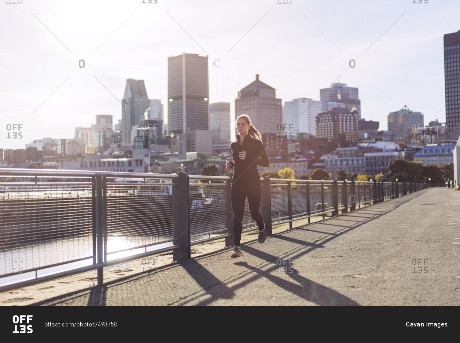 Woman running by railing in city during sunrise - Stock Image - Everypixel