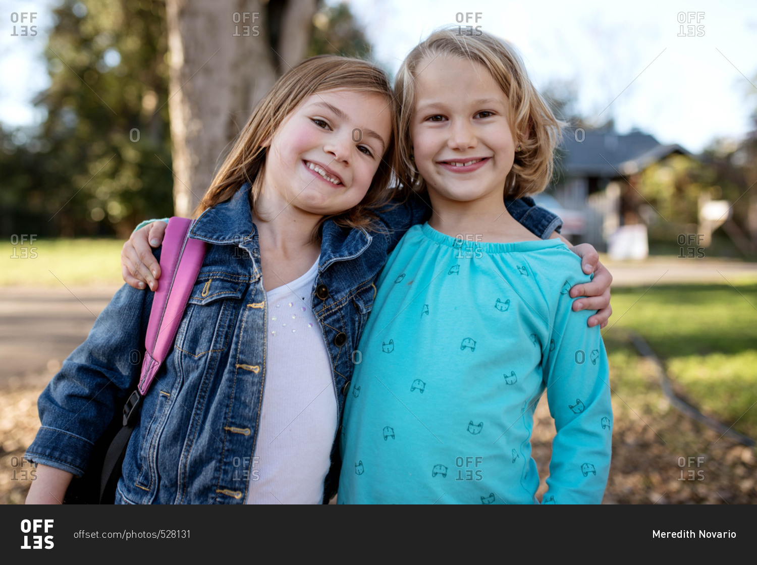 Two girls standing with their arms around each other stock photo - OFFSET