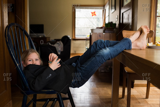 Girl eating snack with feet up on table stock photo - OFFSET