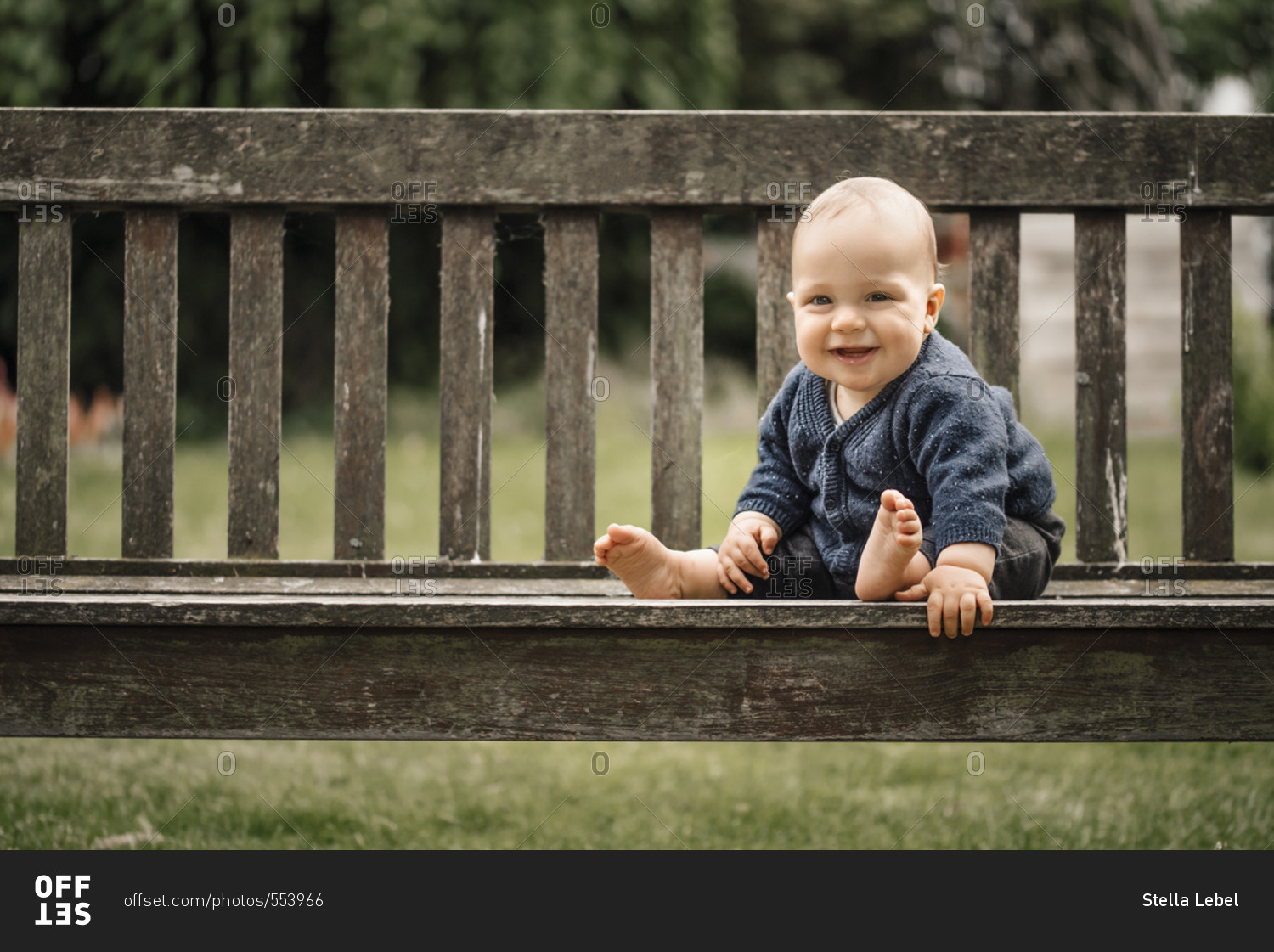 Baby sitting on a wooden bench stock photo - OFFSET