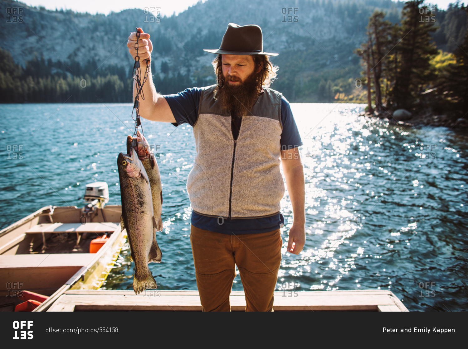 Man holding up freshly caught fish stock photo - OFFSET