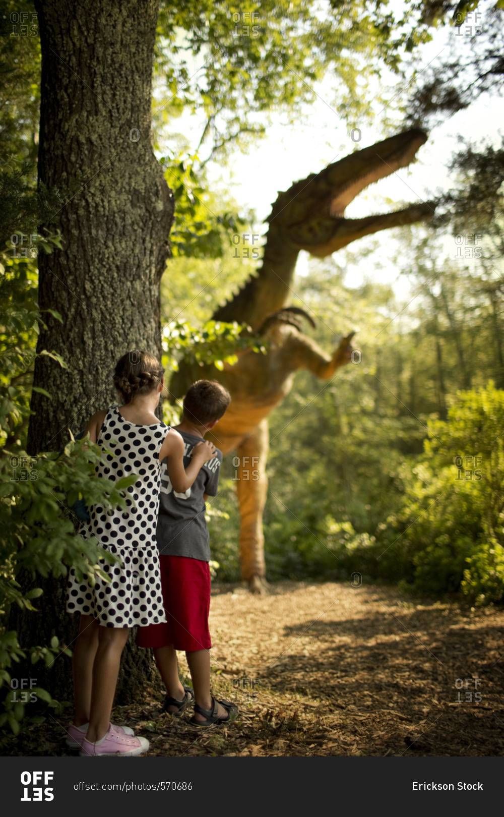 Children hiding from a dinosaur stock photo - OFFSET
