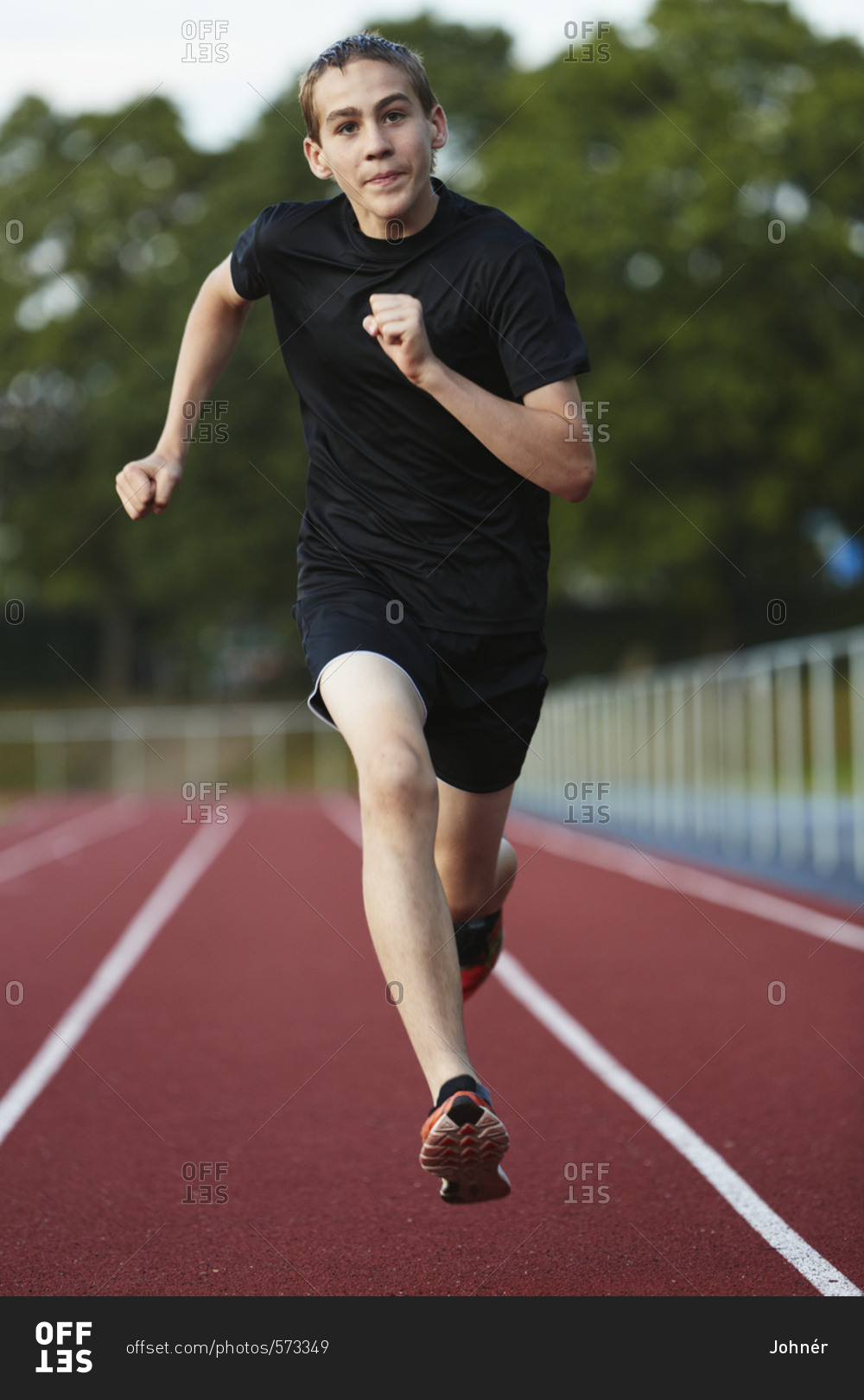 Teenage boy running in sports track stock photo - OFFSET