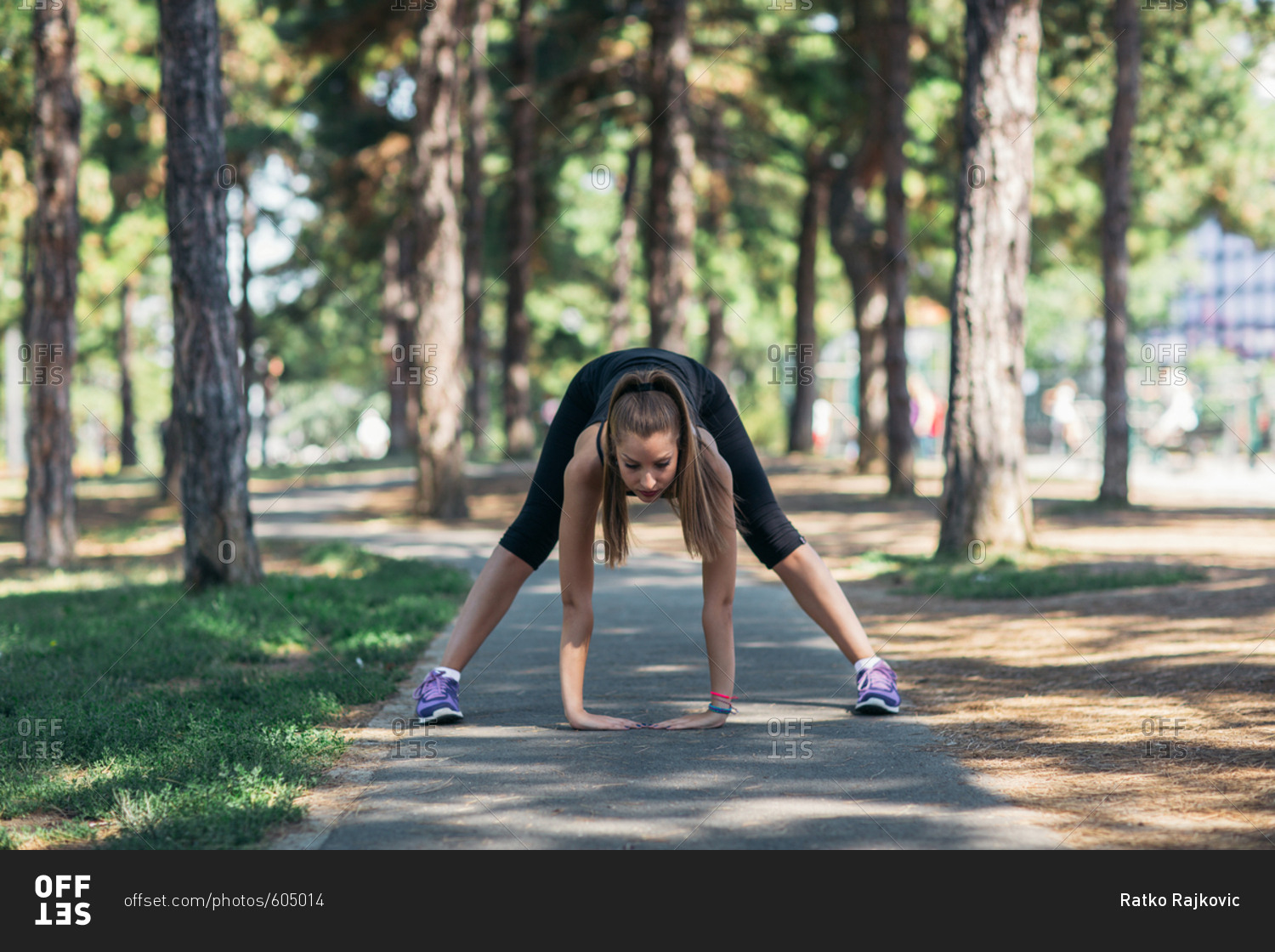 Woman touching ground to stretch before working out stock photo - OFFSET