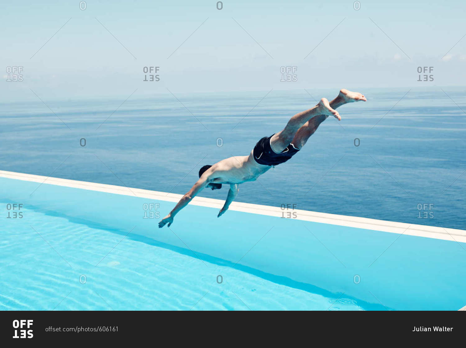 Man diving into seaside pool stock photo - OFFSET