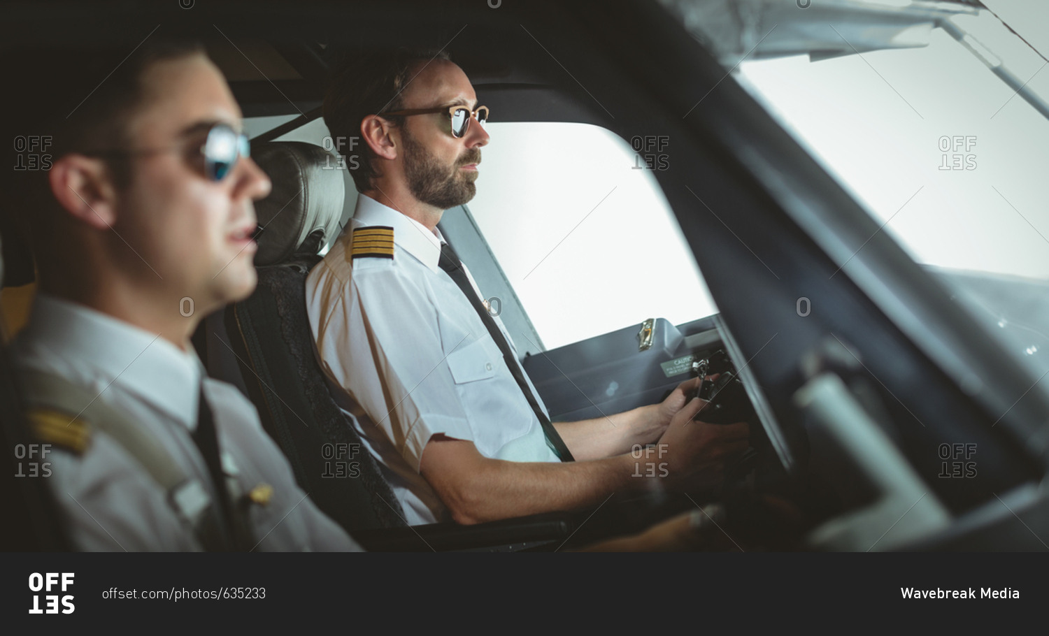 Side view of pilot and copilot flying an airplane stock photo - OFFSET