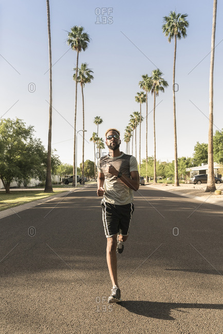 Black man running on street in neighborhood - Stock Image - Everypixel