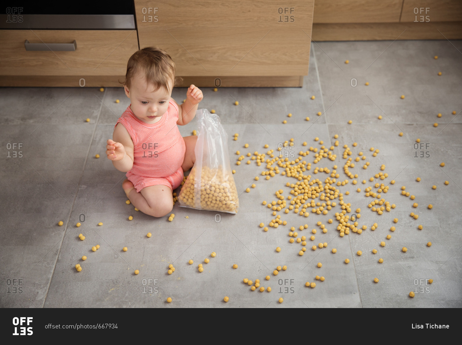 High angle view of baby making mess with bag of cereal stock photo - OFFSET